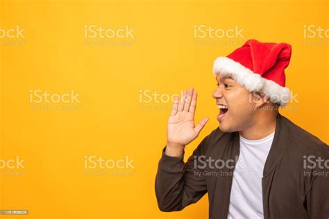 크리스마스 모자를 쓰고 손으로 텍스트 광고를 위해 빈 공간으로 외치는 아시아 남자 메리 크리스마스와 고립 된 노란색 배경을 가진 행복한 새해 사람들 30 34세에 대한 스톡