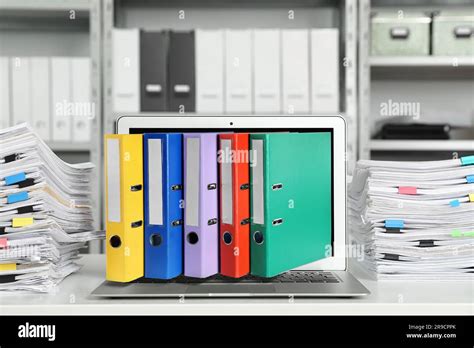 Digital Archive Laptop With Folders Sticking Out Of Screen In Office