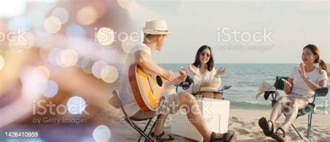 행복한 친구는 캠핑 텐트 근처 모래 해변에서 휴가를 보내고 함께 미소 짓는 캠프에서 기타를 연주하고 박수를 치는 재미를 가지고 있습니다 20 24세에 대한 스톡 사진 및