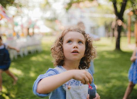 Small Girl Sitting Outdoors In Garden In Summer A Birthday Celebration