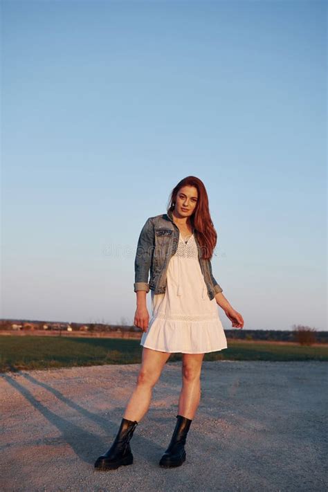 Redhead Woman In Skirt Standing And Posing For A Camera On The Road At Evening Time Stock Photo
