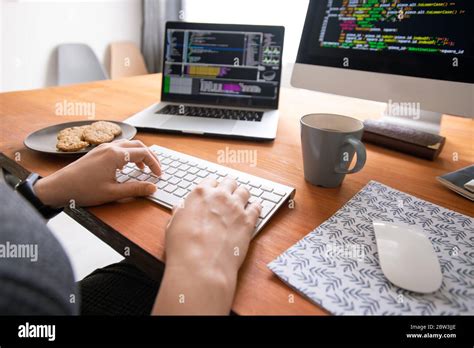 Close Up Of Unrecognizable Programmer Sitting At Desk With Coffee And Cookies And Creating Code
