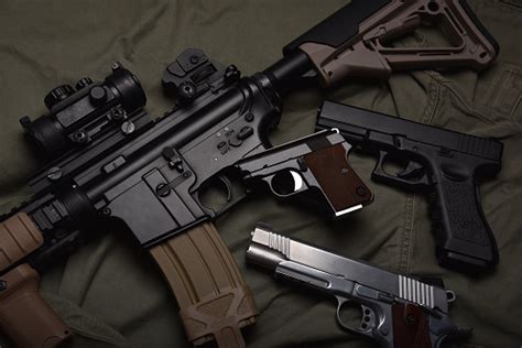 Weapons And Military Equipment For Army Assault Rifle Gun And Pistol On Green Military Uniform
