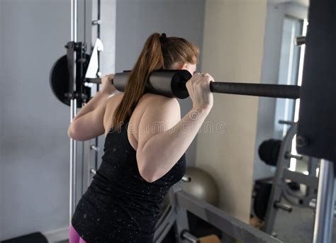 Plus Size Woman Doing Exercises On Smith Machine Squats On A Simulator