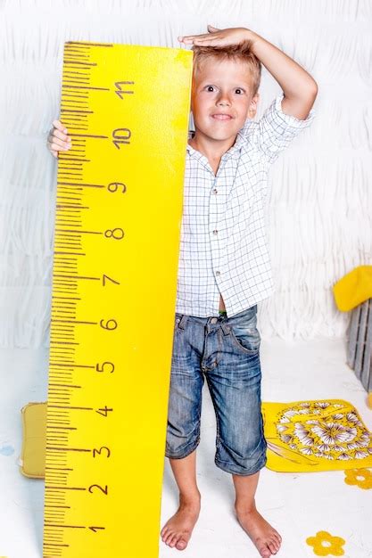 Premium Photo Portrait Of Cute Smiling Boy Measuring Height At Home