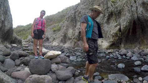 An Older Man And A Young Woman Hike Along A River In A Canyon Stock