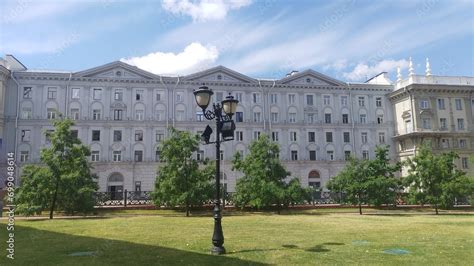 In The City Square Trees Grow On Grassy Lawns And Metal Poles With