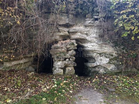 A Rock Cave Overgrown With Grass And Trees On A Clear Day Stock Image