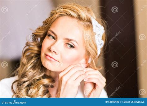Elegant Blonde Bride Putting On Earrings Closeup Preparing For Wedding