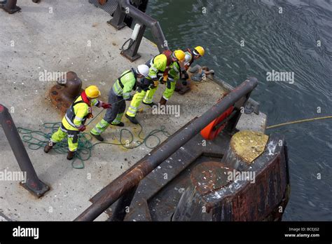 Shore Crew Pull Safety Line Connected To Ship Rope Onto Quay While