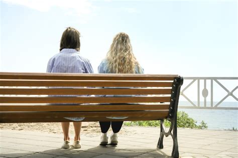 Deux Jeunes Femmes Assises Sur Un Banc Pr S De La Mer Photo Premium