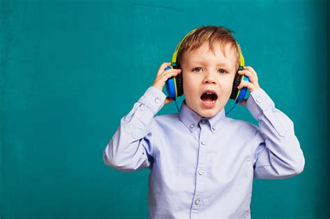 서 고 녹색 파란 벽에 스마트폰 통해 헤드폰에서 음악을 듣고 밝은 헤드폰에 잘생긴 작은 세련 된 소년 귀여운에 대한 스톡 사진 및 기타 이미지 Istock