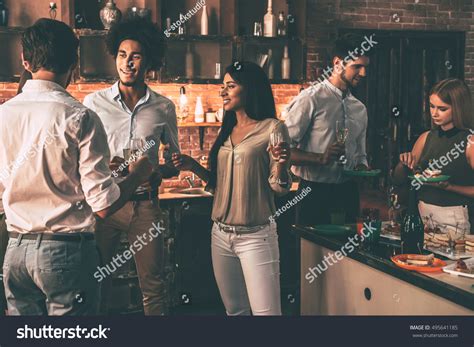 家庭聚会与最近的朋友 一群欢快的年轻人享受家庭派对小吃和饮料，同时在厨房沟通库存照片495641185 Shutterstock