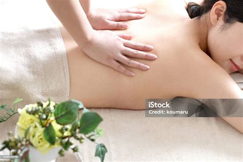 Esthetician Working On A Young Asian Woman Lying Face Down On Bed