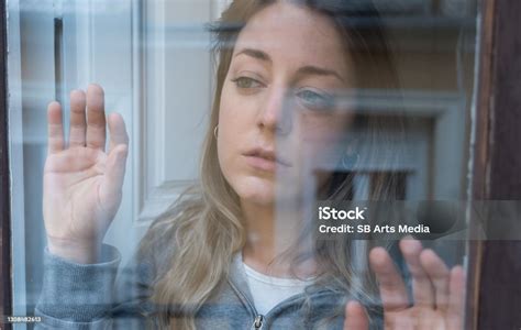 젊은 아름다운 우울한 불행한 백인 여성은 집에서 창문을 통해 걱정하고 슬퍼보입니다 쓸모없고 고통스러웠습니다 근접 촬영 우울증과 정신 건강 개념 사색에 대한 스톡 사진 및
