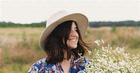 시골의 여름 파란색 빈티지 드레스와 모자를 쓴 세련된 젊은 여성이 여름 초원에서 흰색 야생화와 함께 걷고 있다 들판에서