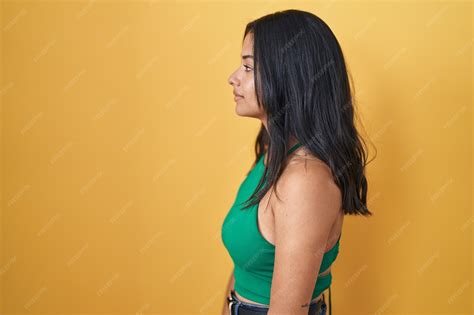 Brunette Woman Standing Over Yellow Background Looking To Side Relax