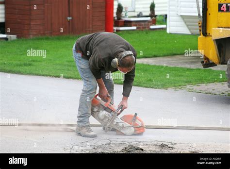 Man Using Petrol Powered Cutting Disk To Cut Asphalt And Wearing Dust
