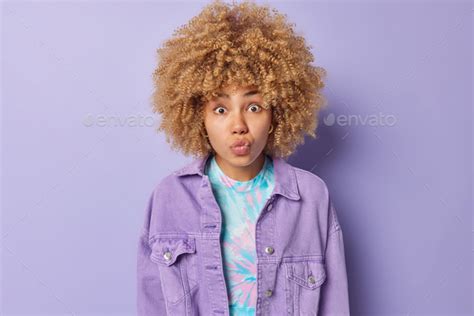 Portrait Of Surprised Curly Haired European Woman Keeps Lips Rounded