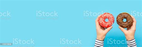 여성의 손은 파란색 배경에 도넛을 들고 있습니다 컨셉 제과 점 패스트리 커피 숍 배너 플랫 레이 상단 보기 도넛에 대한 스톡 사진 및 기타 이미지 Istock
