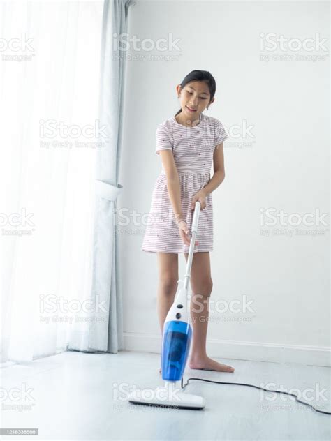 Asian Girl Using Vacuum Cleaner Girl Standing Near Window At Home