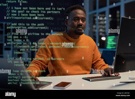 African American Developer Typing Codes On Computer While Sitting At His Workplace In Dark