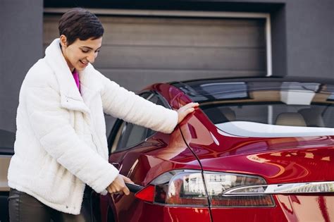 Premium Photo Woman Charging Electro Car With Charging Pistol By The House