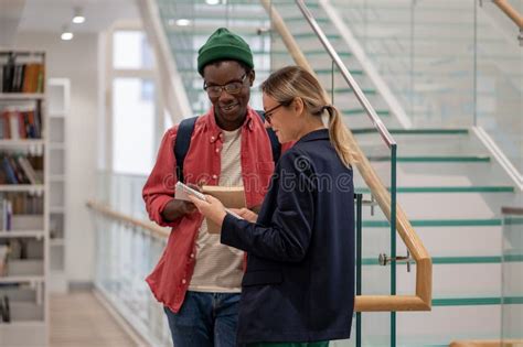 Two Smiling Diverse Students Talking Discussing Homework While Standing