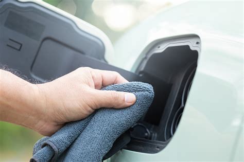 자동차 소유자의 손은 전기 자동차 충전 커넥터를 천으로 조심스럽게 청소하여 사용 전후에 먼지와 습기가 없는지 확인합니다 안정적인