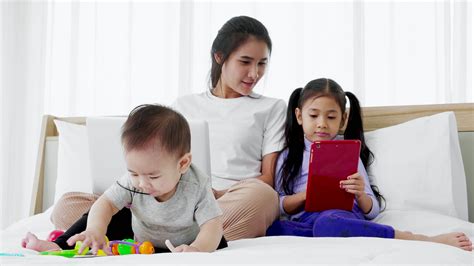 Busy Mother With Two Daughters Multitasking With Laptop Super Mom
