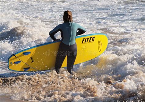 Surfer Girl Entering The Ocean With Yellow Surfboard Editorial Stock
