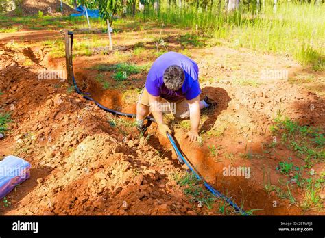 Worker In Garden Digging Installing Pvc Water Pipe For New Irrigation