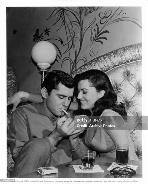 Man Lighting Cigarette In Front Of A Smiling Edy Williams In A Scene