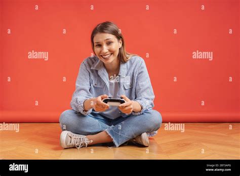 Excited Delighted Woman Playing Video Games While Holding A Game Console In Hands And Sitting