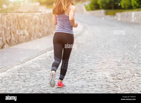 Back View Of Running Woman On Cobbled Road With Copy Space Aside Rear
