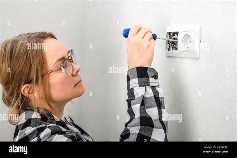 Woman With Screwdriver Repairing An Electrical Socket Woman Installing An Electrical Outlet In