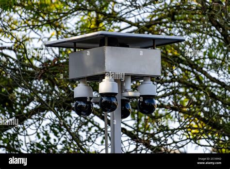 Four Cctv Cameras On Metal Light Pole Blue Sky And Green Tree