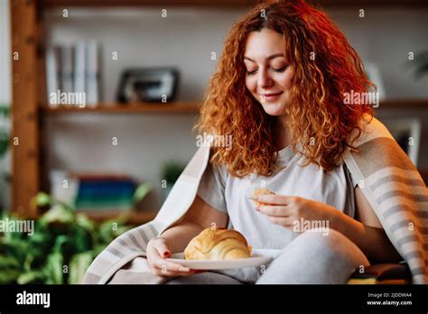A Hungry Redhead Sitting At Her Cozy Home In The Morning And Having
