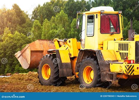 A Yellow Bulldozer Is Compacting A Green Mass Of Cut Grass Stock Image