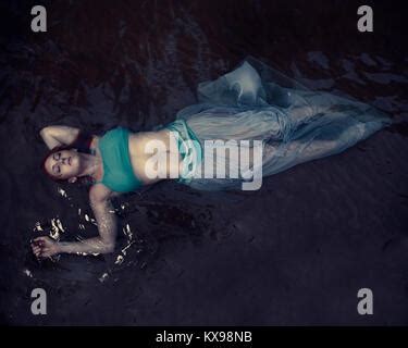 Naked Woman Submerged Under Water Floating On Her Back In Swimming Pool