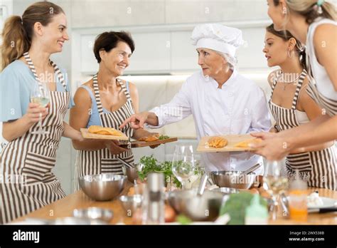 Elderly Woman Chef Teaches Group Of People How To Cook Chicken Stock