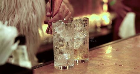 Bartender Is Pouring Cocktail In A Glass With A Ice Through Metal Stiring Process Of Making A