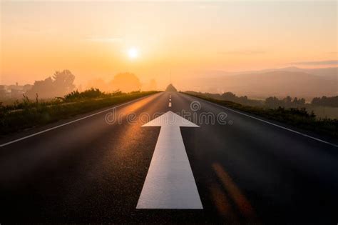 Asphalt Road With White Arrow Pointing Toward Glowing Sunset Horizon Stock Illustration