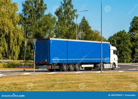 Big Blue Delivery Lorry Maneuvering In The Narrow Pass Of A Landscaped
