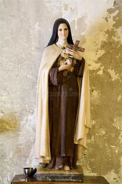 Old Statue Of Saint Therese Of Lisieux Against A Weathered Wall Stock