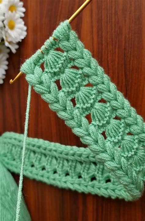 A Green Crochet Piece Sitting On Top Of A Wooden Table Next To White