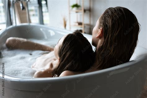 Back View Of Young Lesbian Women Relaxing In Bubble Bath Together
