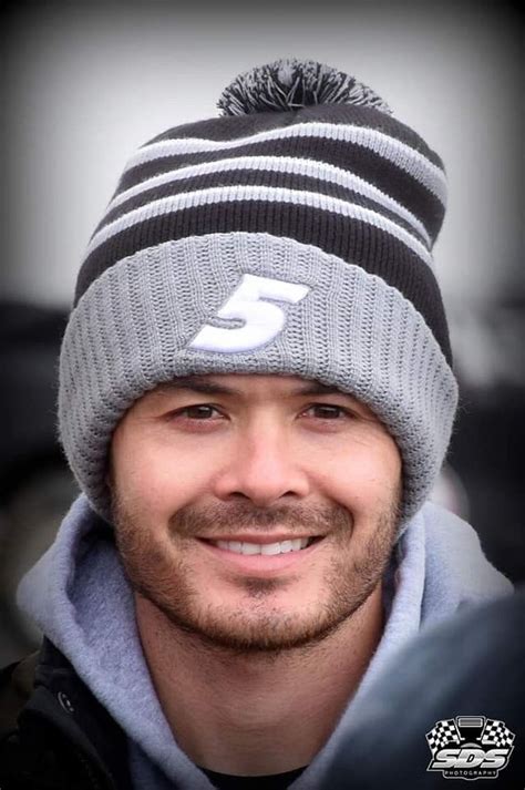 A Smiling Man Wearing A Gray And Black Striped Beanie With Pom Pom