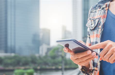 손 입력 스마트 폰과 일출 및 건물 배경과 도시에서 야외 응용 프로그램 장치와 터치 스크린 작업 검색을 사용하여 잘 생긴 남자를 닫습니다 세계를 연결하는 5g 기술 5g에