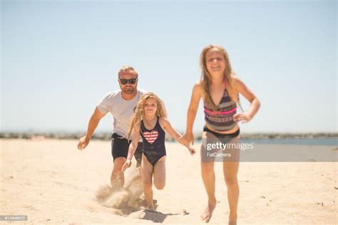 Dad Chases His Daughters Down The Beach On A Sunny Afternoon High Res